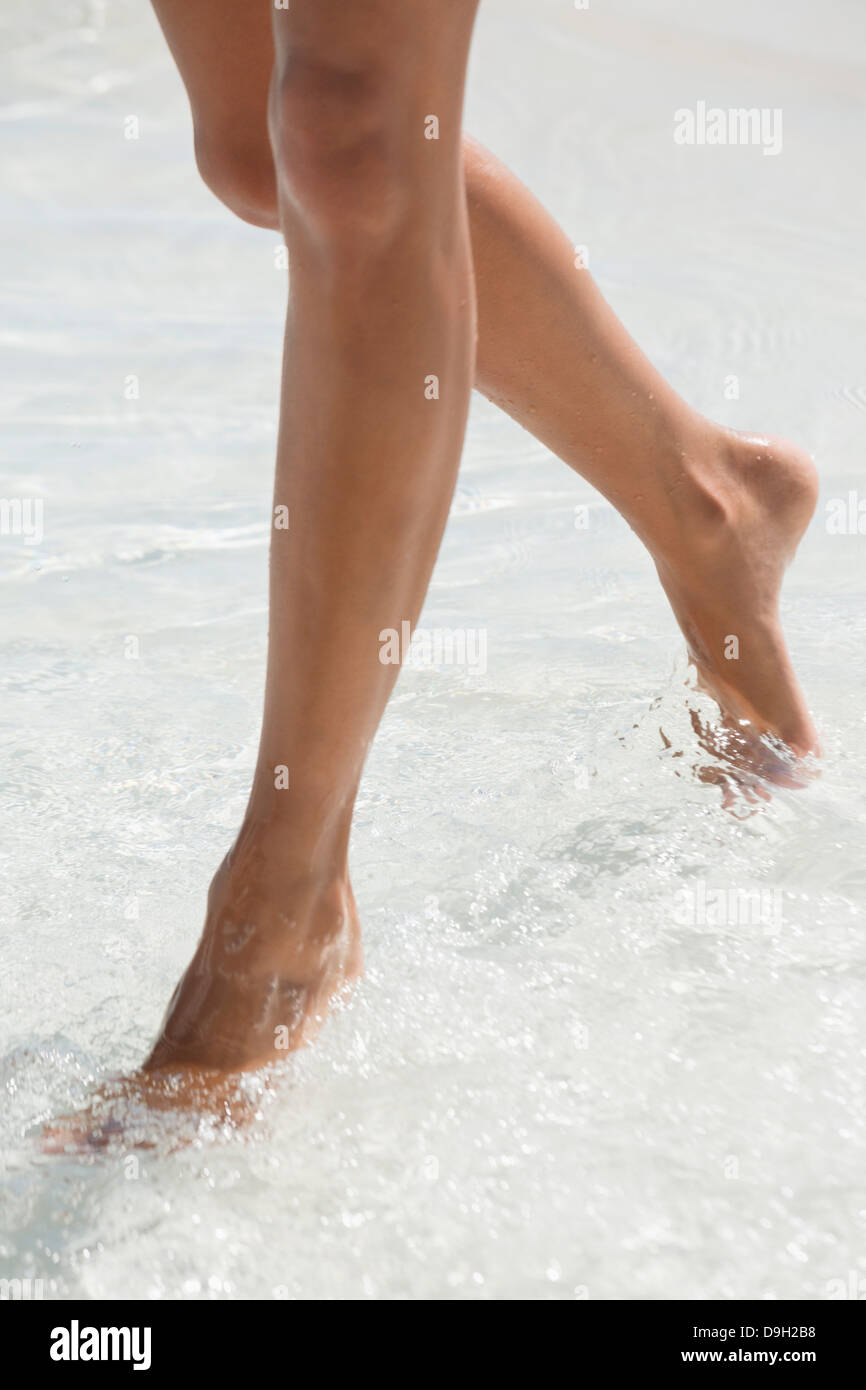 Woman walking in water on the beach Stock Photo - Alamy