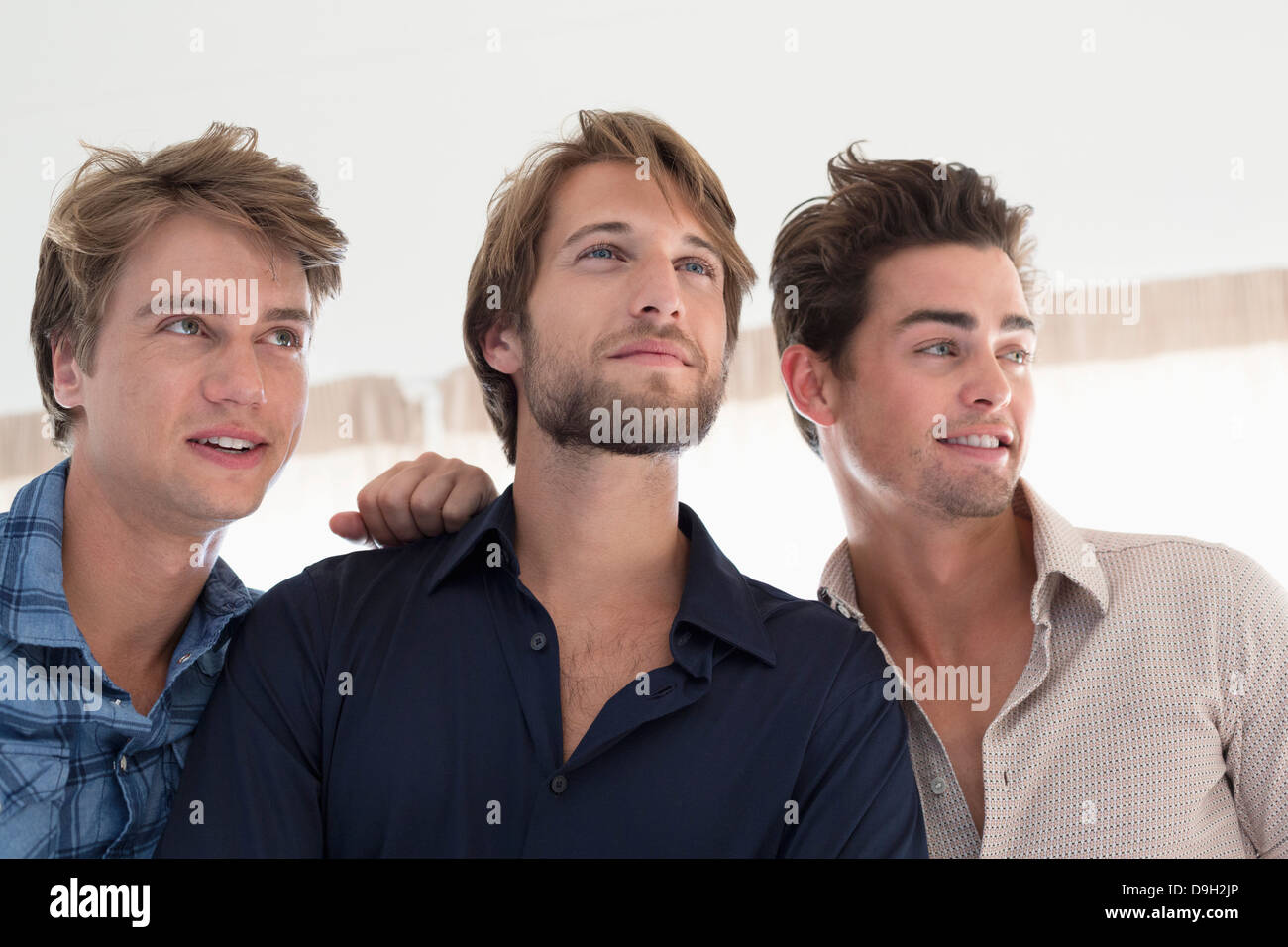 Three male friends looking away Stock Photo - Alamy