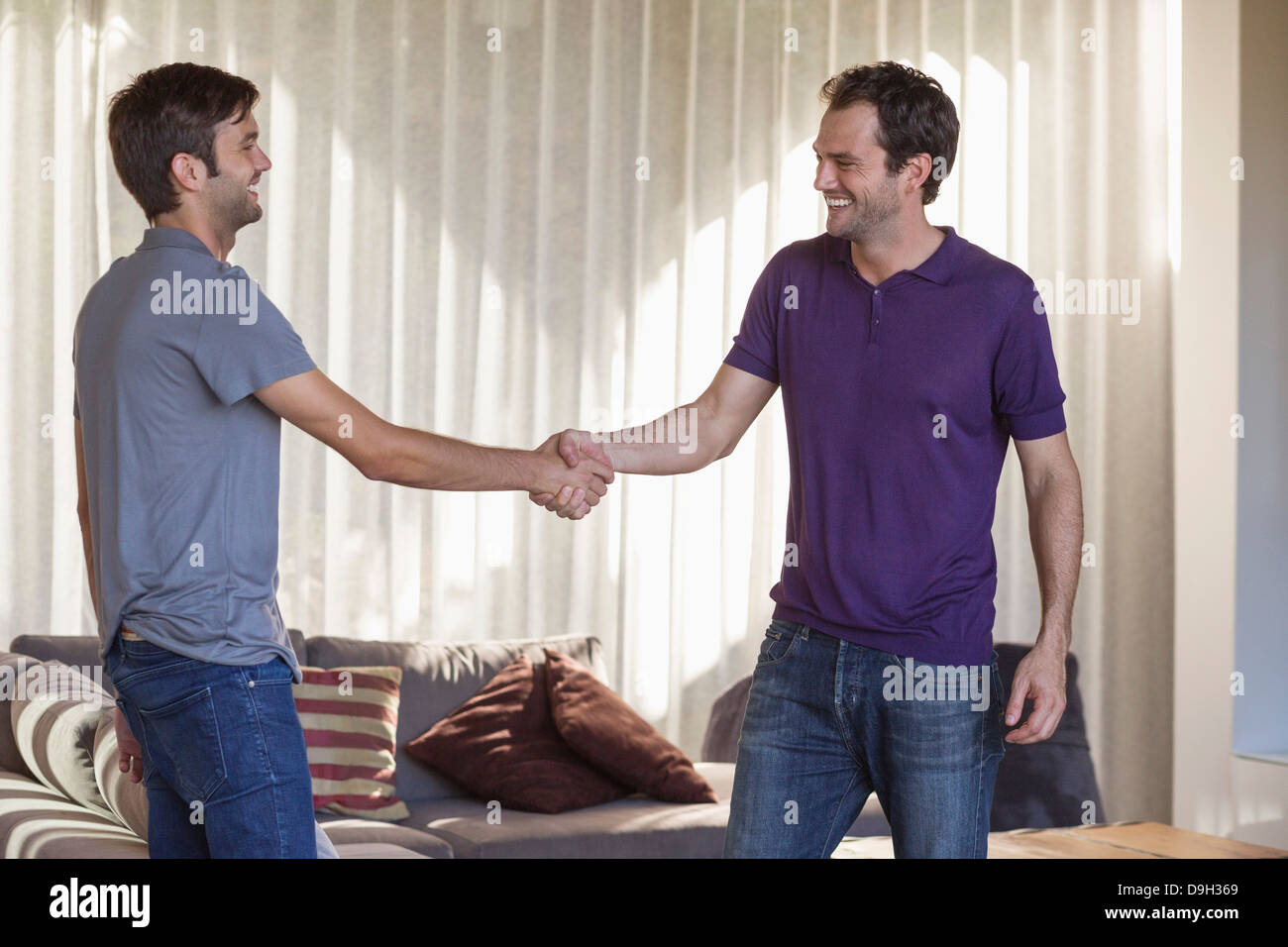 Two friends shaking hands and smiling Stock Photo - Alamy