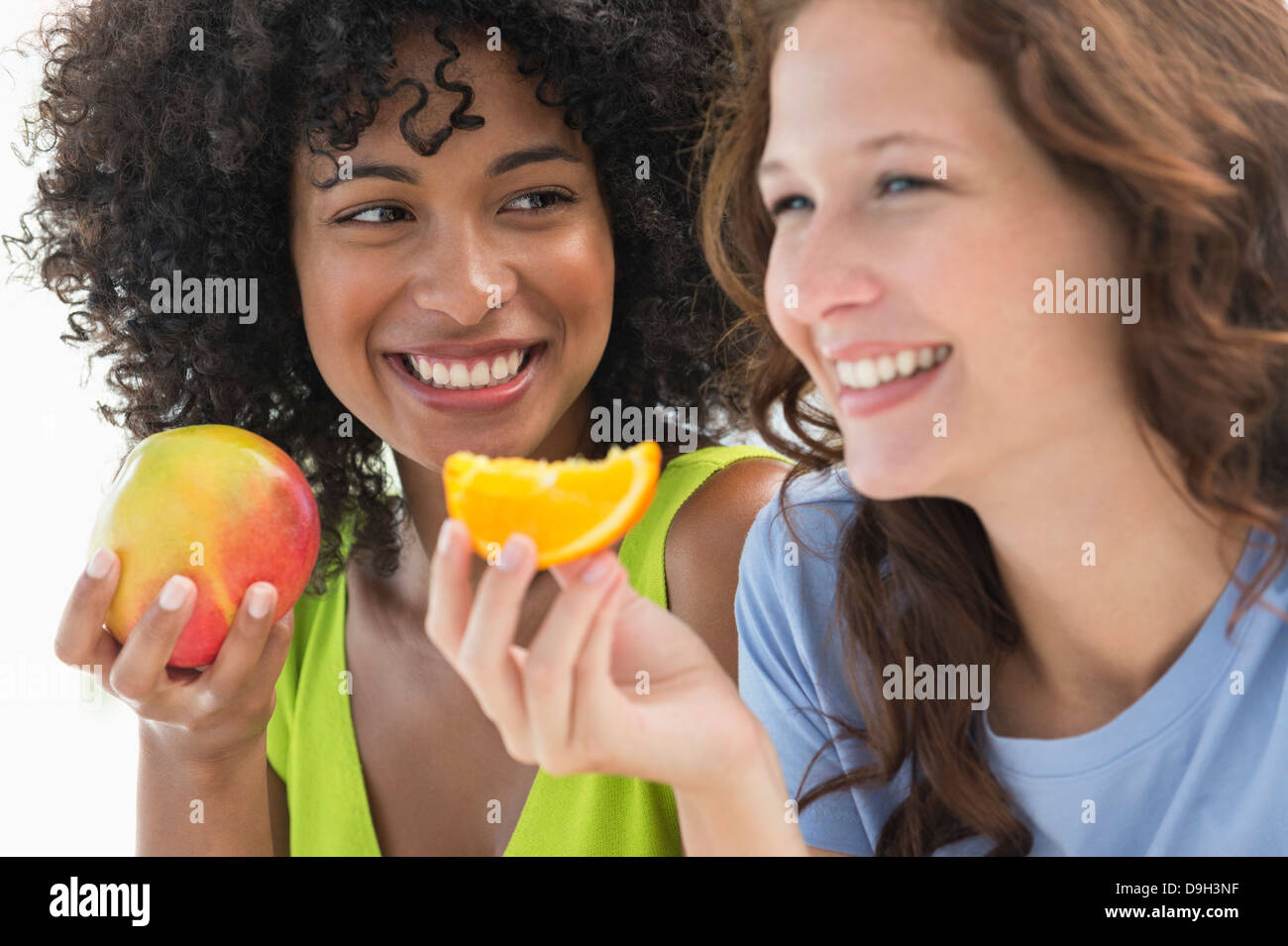 Close-up of two smiling female friends eating fruits Stock Photo - Alamy