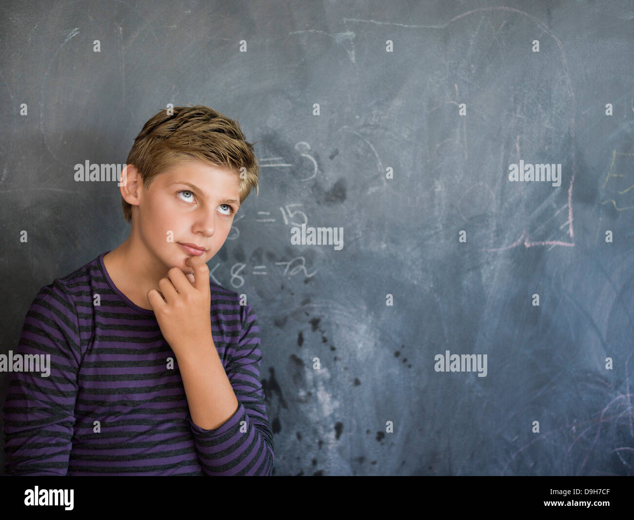 Boy thinking in front of a blackboard in a classroom Stock Photo - Alamy
