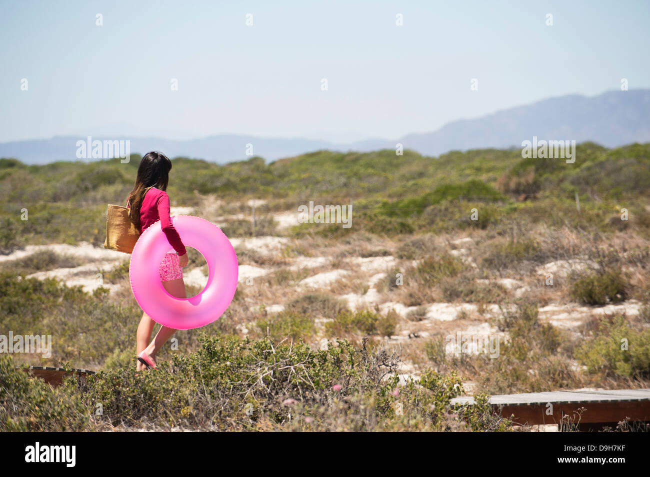 Woman holding an inflatable ring and walking on a boardwalk on the ...