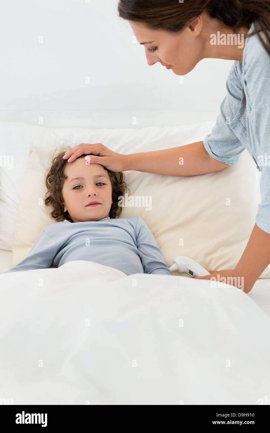 Woman touching forehead of her son looking sick Stock Photo - Alamy
