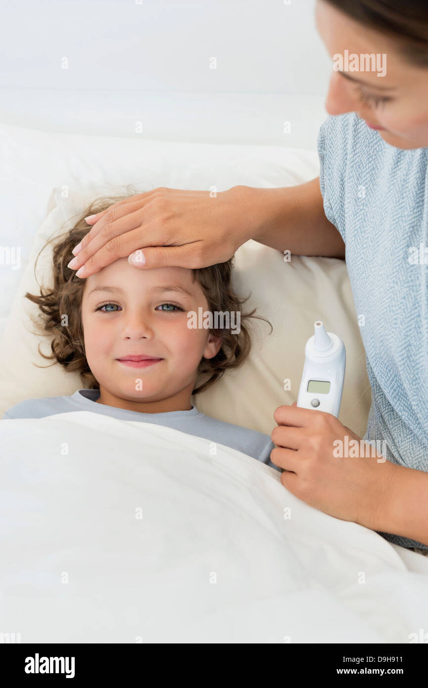 Woman touching forehead of her son looking sick Stock Photo - Alamy