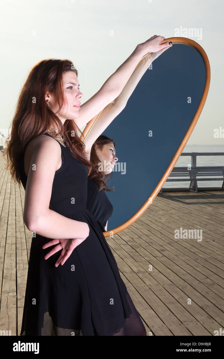 thoughtful young woman looks at the reflection in the mirror - solitude ...