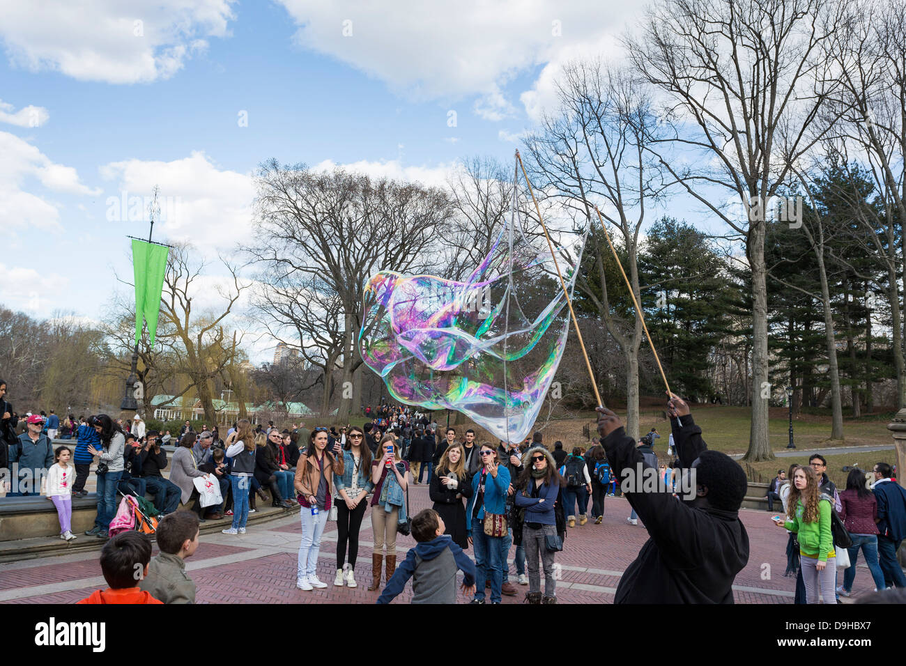 Crowd observing a street performer blowing bubbles - kids playing ...