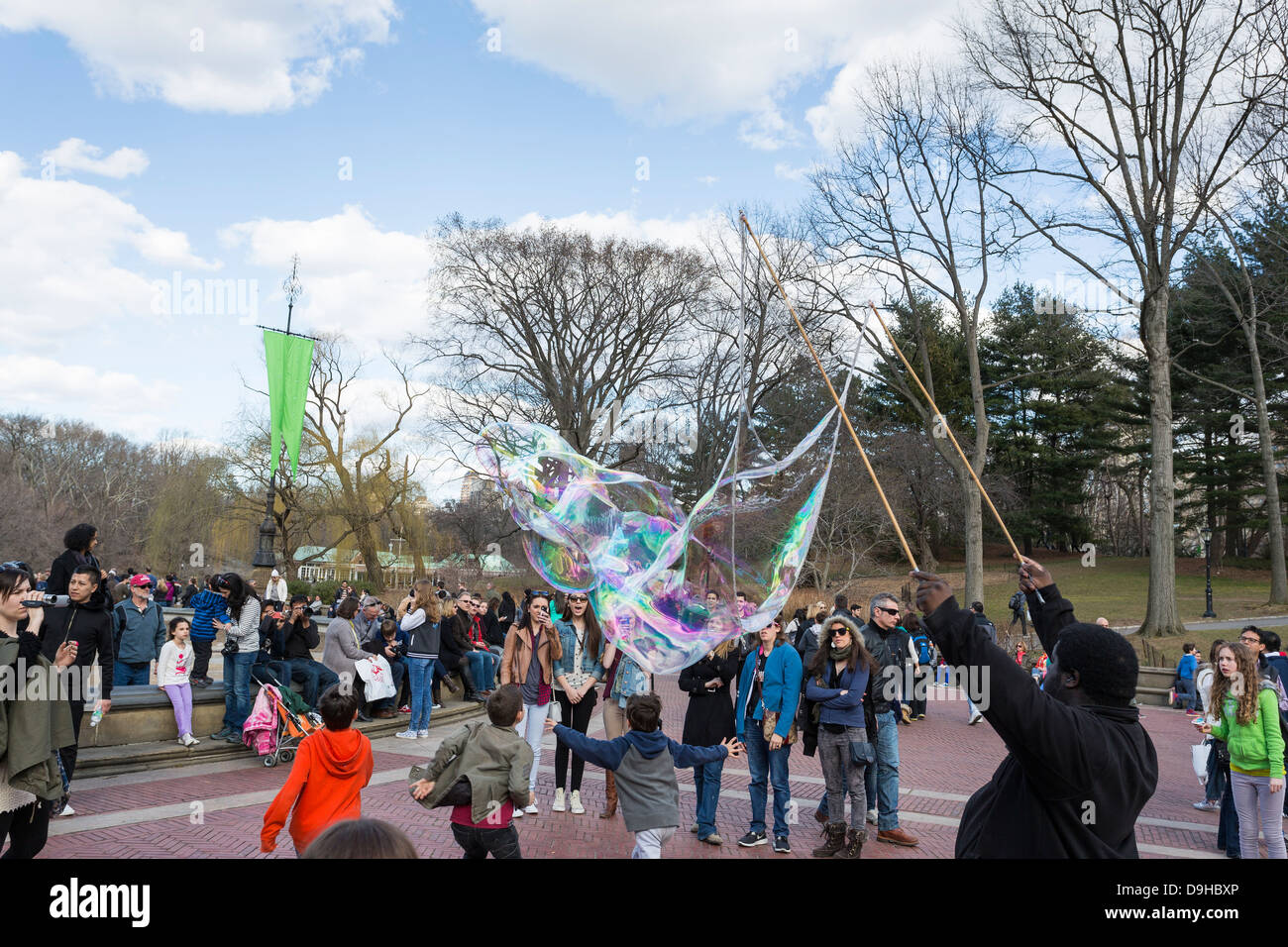 Crowd observing a street performer blowing bubbles - kids playing ...
