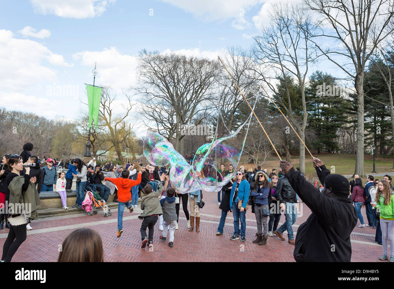 Crowd observing a street performer blowing bubbles - kids playing ...
