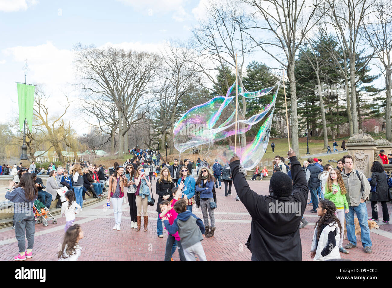 Crowd observing a street performer blowing bubbles - kids playing ...