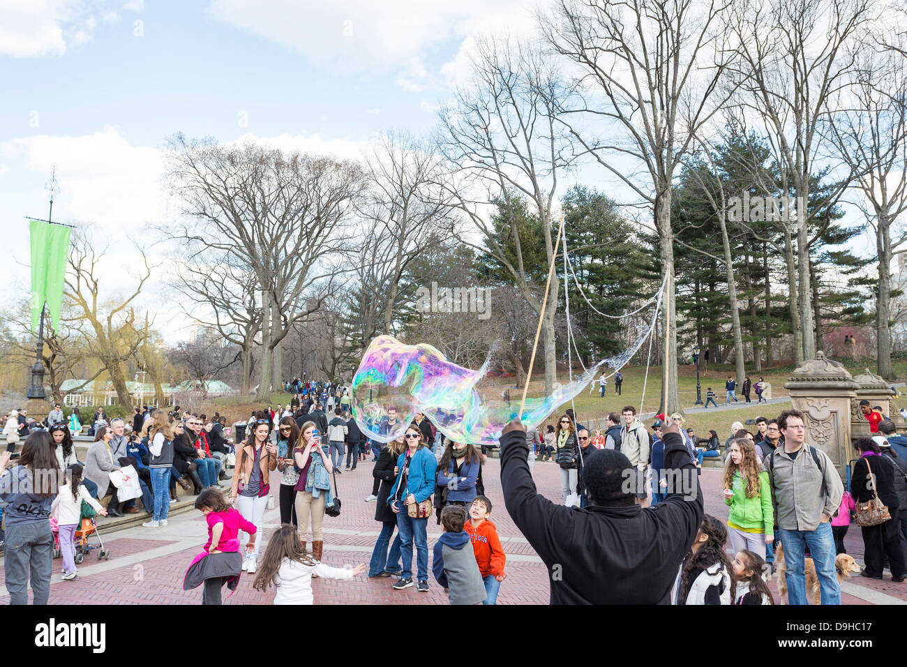 Crowd observing a street performer blowing bubbles - kids playing ...