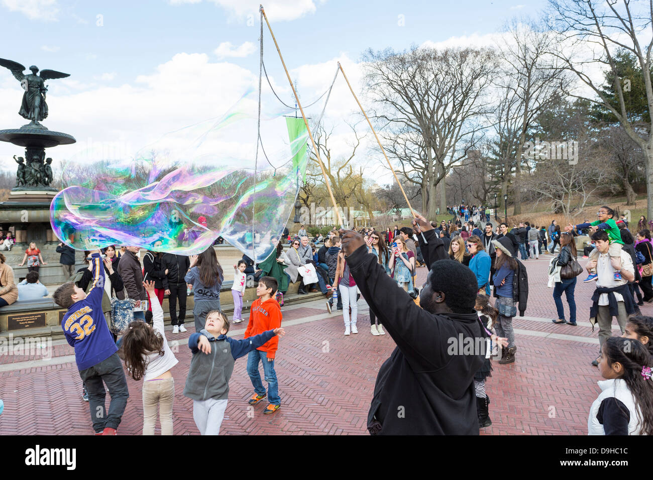 Crowd observing a street performer blowing bubbles - kids playing ...