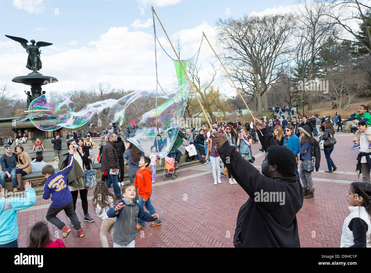 Crowd observing a street performer blowing bubbles - kids playing ...
