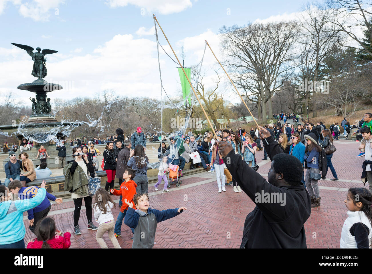 Crowd observing a street performer blowing bubbles - kids playing ...