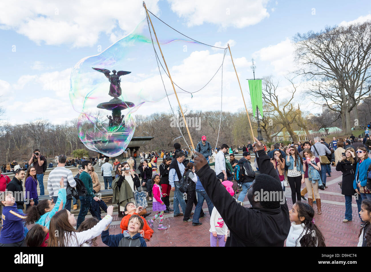Crowd observing a street performer blowing bubbles - kids playing ...