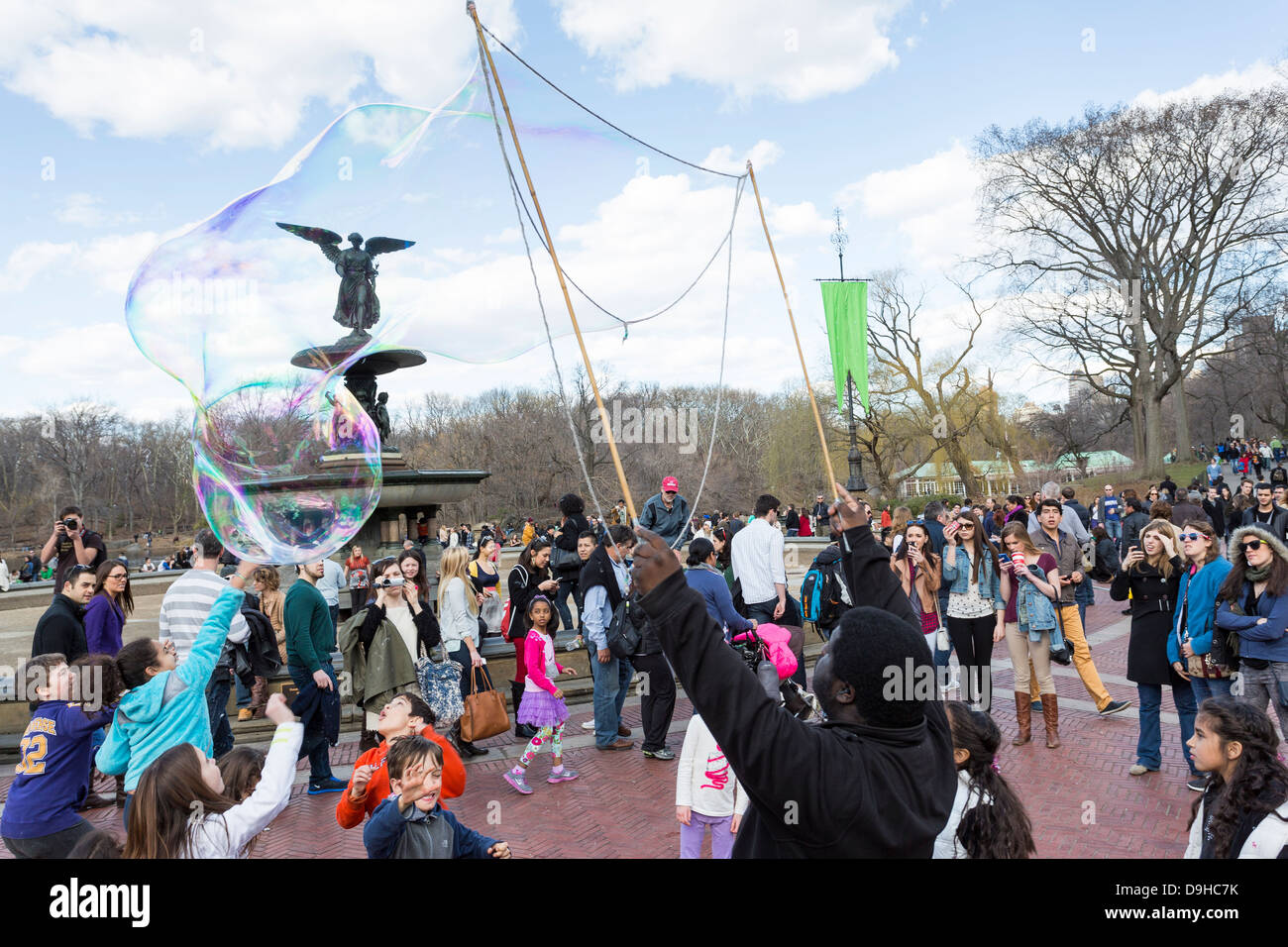 Crowd observing a street performer blowing bubbles - kids playing ...