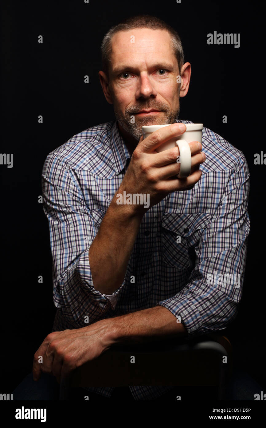 A dramatic portrait of a 40-something male with a soft smile looking at ...