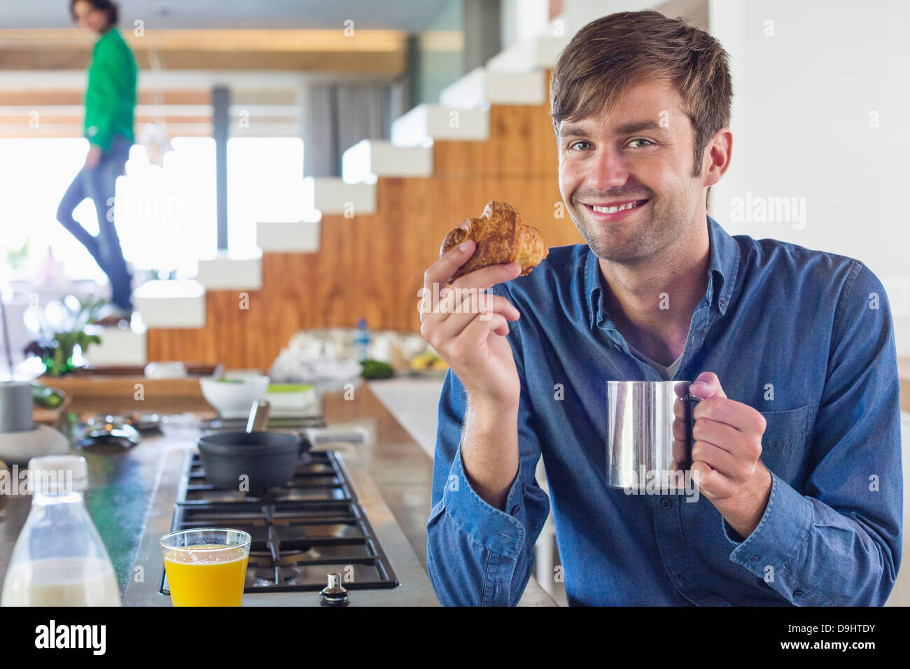 Man having breakfast at a kitchen counter with his wife in the ...