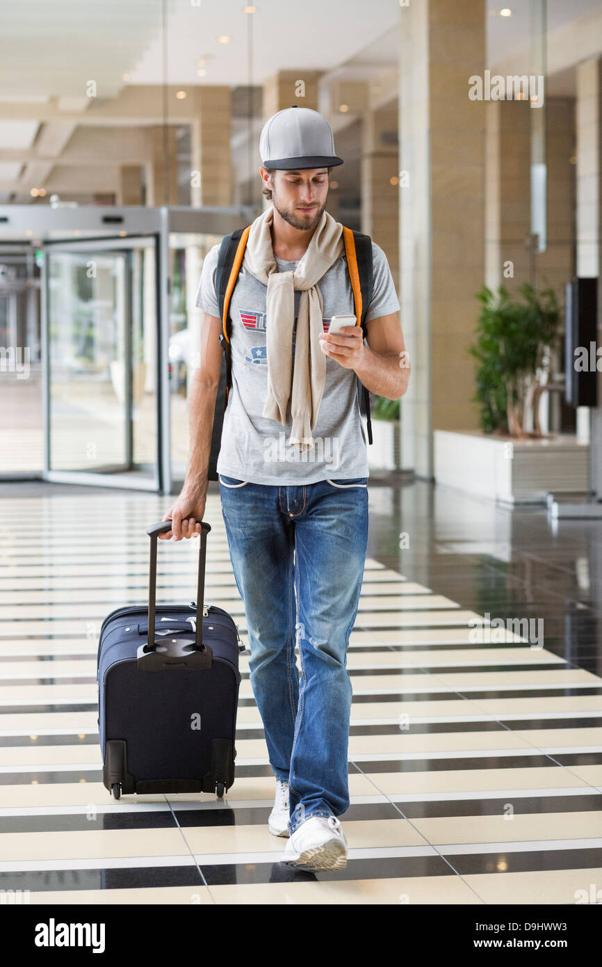 Man pulling his luggage at an airport and using a mobile phone Stock ...