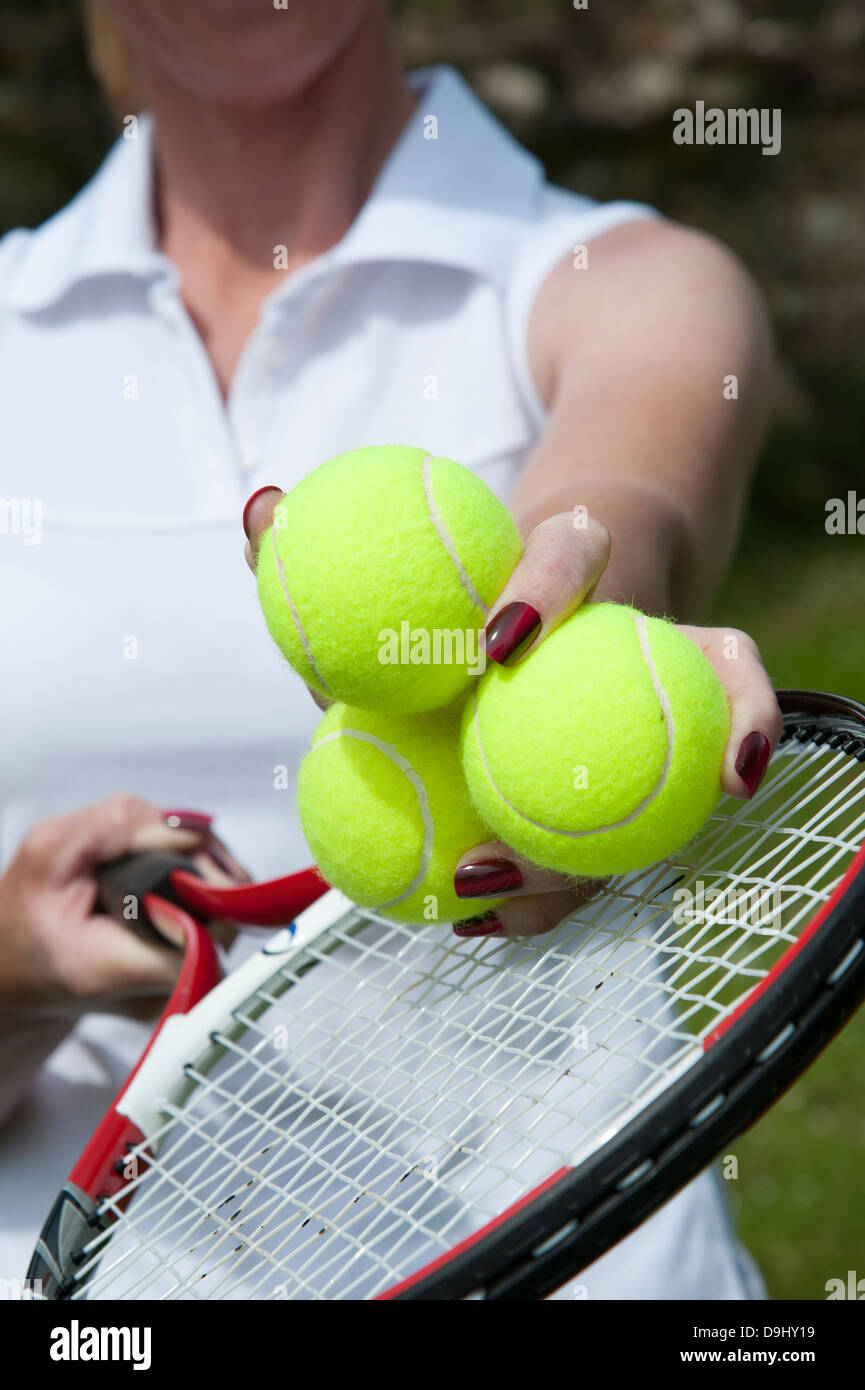 Tennis balls in a player's hand above racquet strings Stock Photo - Alamy