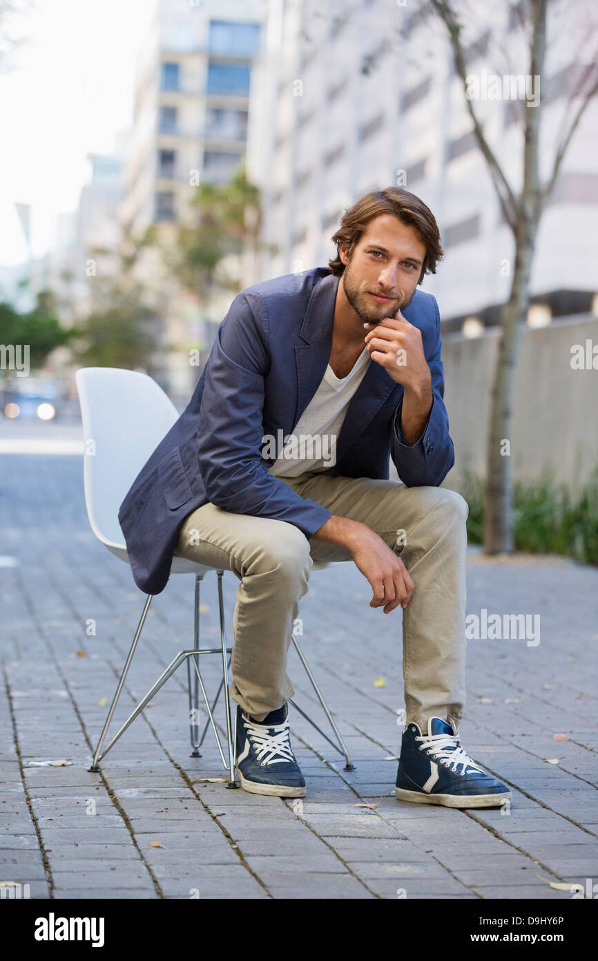 Portrait of a man sitting on a chair on a street Stock Photo - Alamy