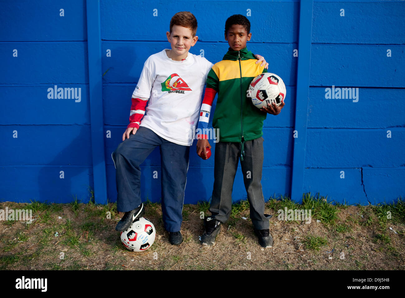 A portrait of two young football players holding a football in ...