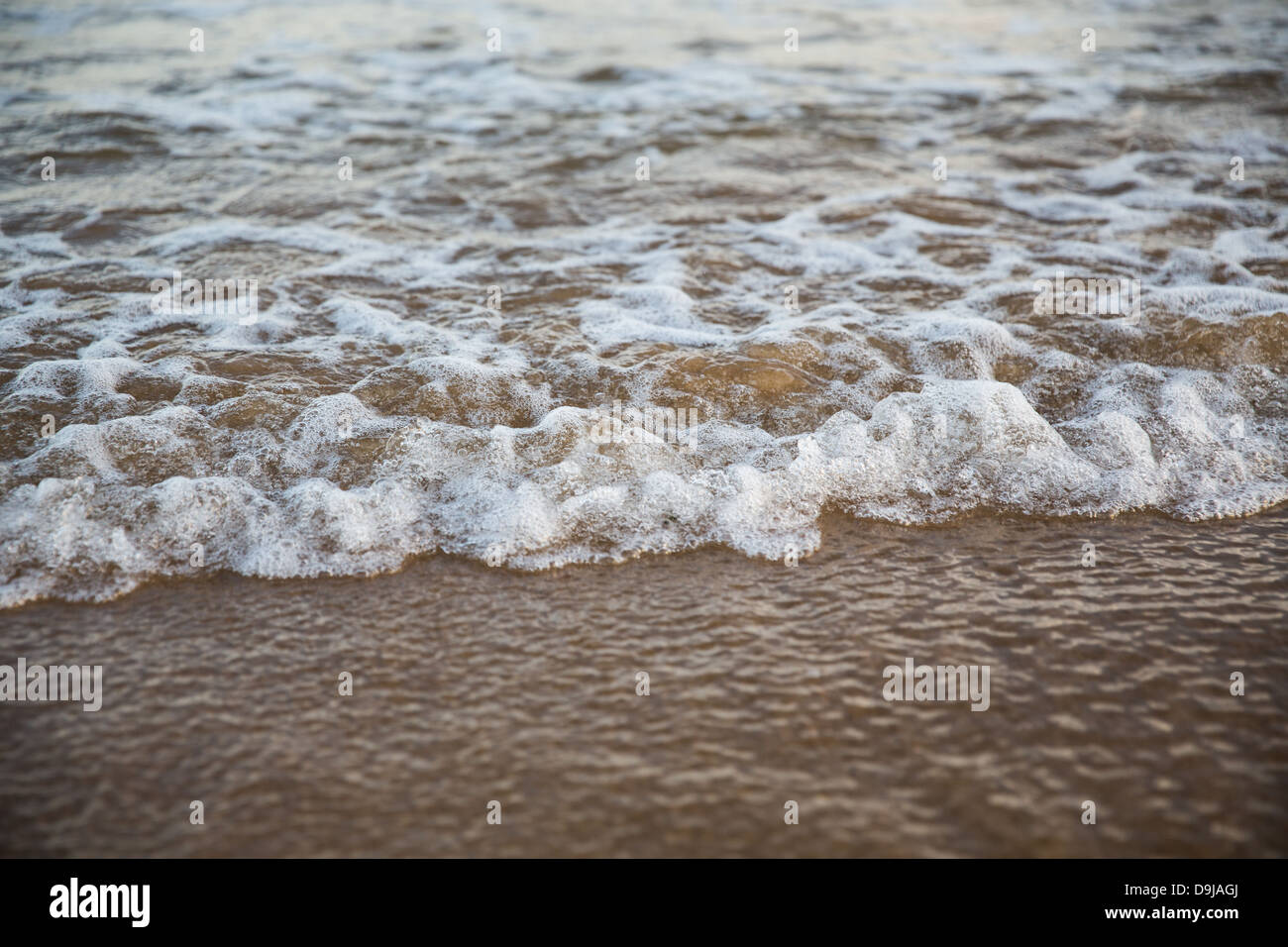 Small wave rolling up the sand Stock Photo - Alamy
