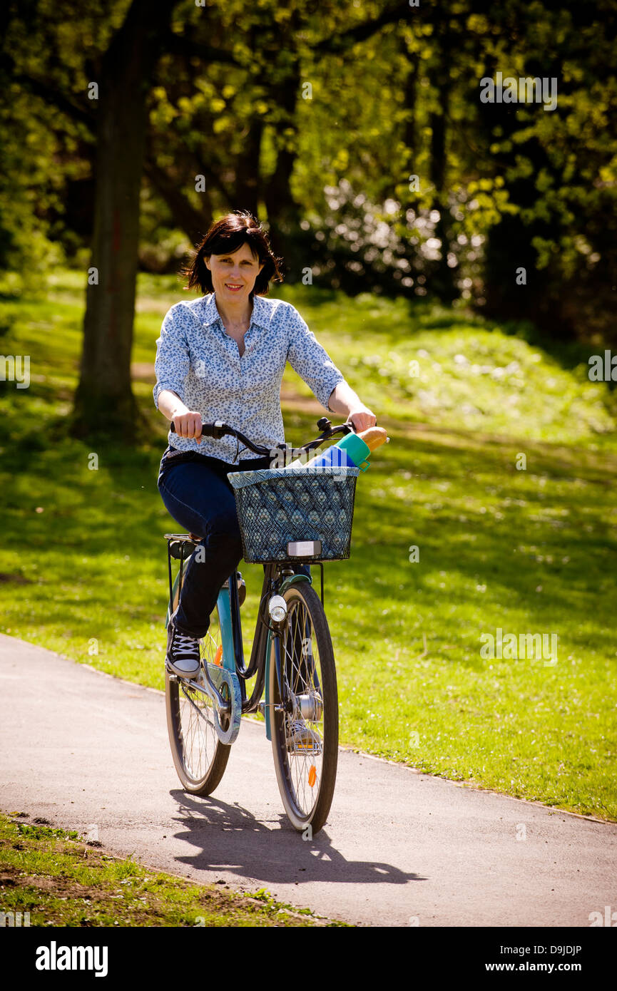 Young casually dressed caucasian woman riding a bike in a UK park Stock ...