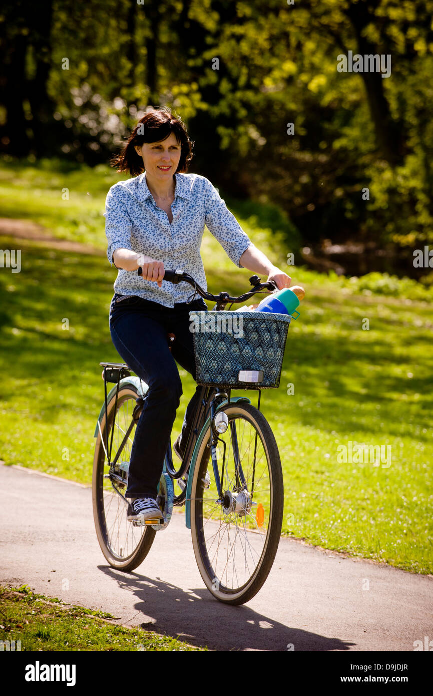 Young casually dressed caucasian woman riding a bike in a UK park Stock ...