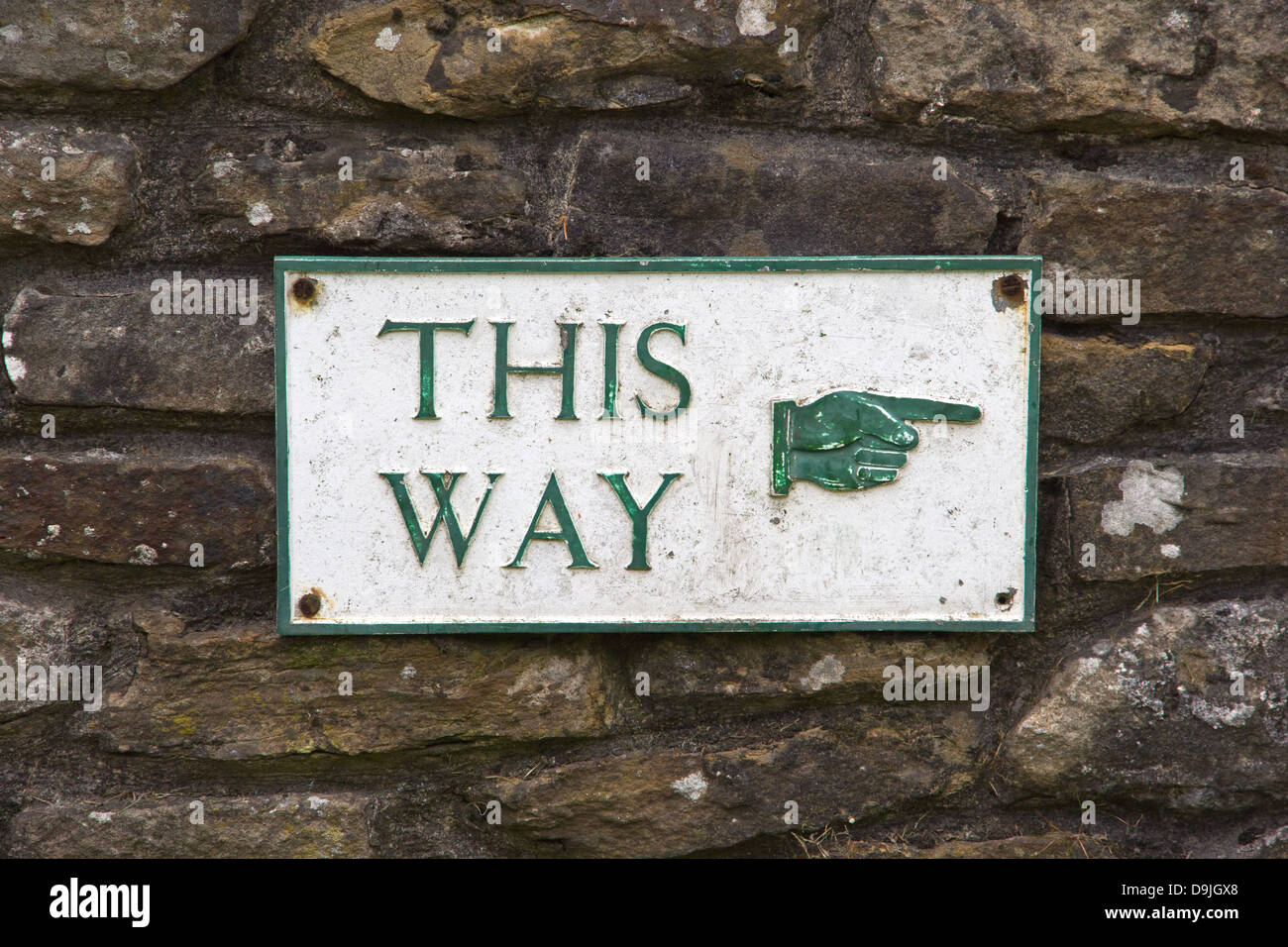 Old This Way sign mounted on stone wall Stock Photo - Alamy