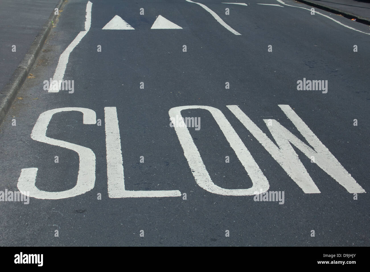 painted road warning saying 'slow' and speed bumps Stock Photo - Alamy