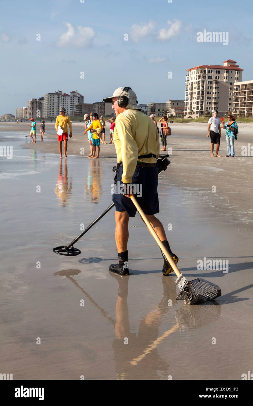 Treasure hunter scanning beach with metal detector and collection ...