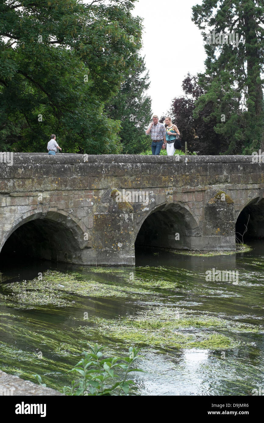 People walking across old stone bridge with river flowing underneath ...