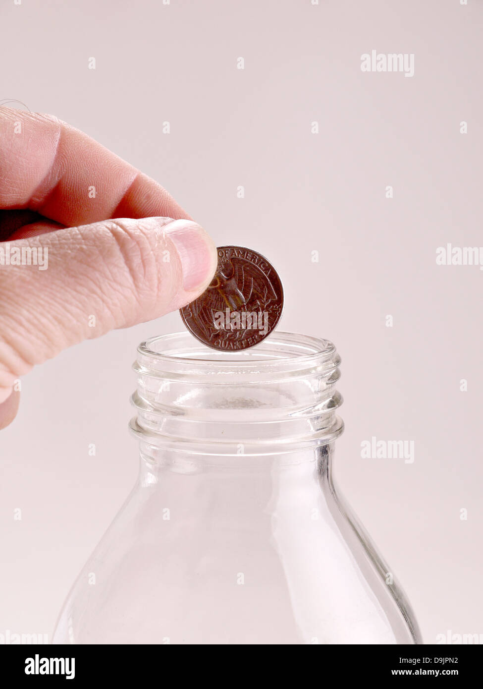 A hand is dropping a US coin into a jar Stock Photo - Alamy