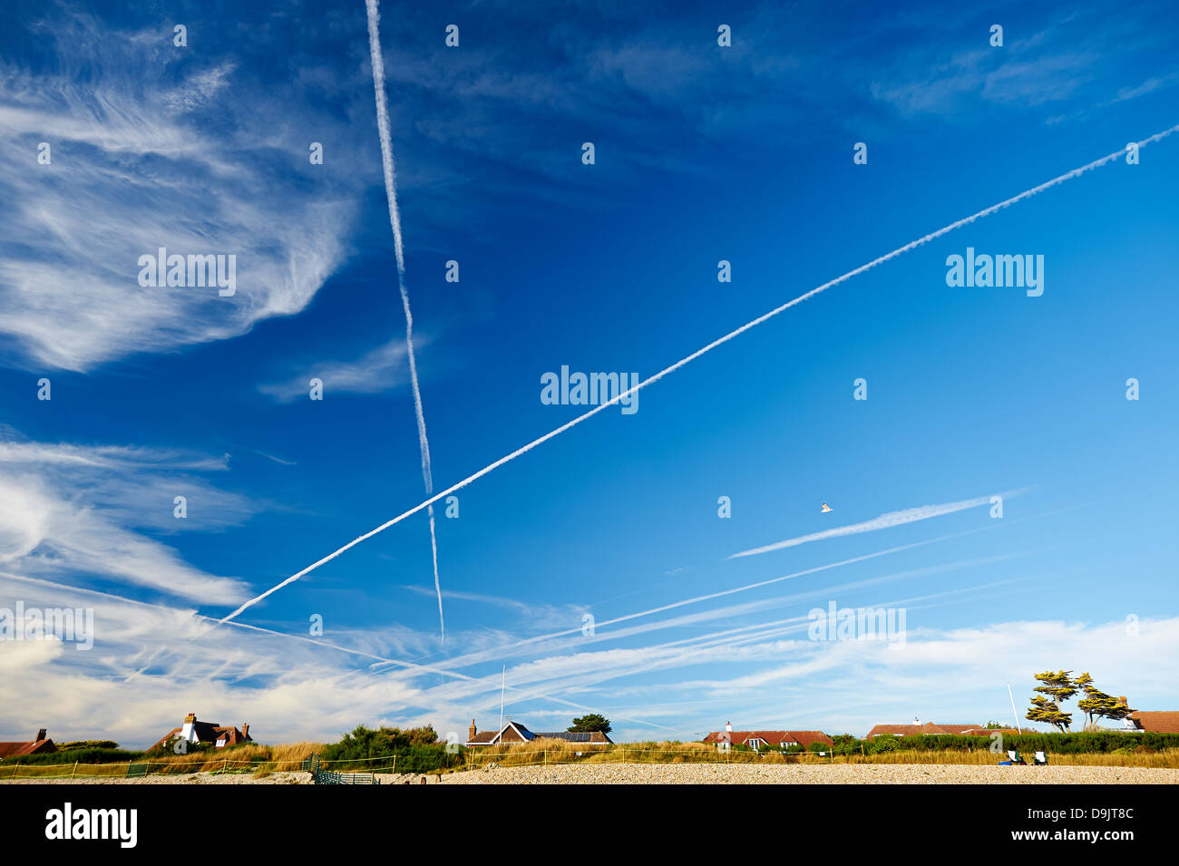 Jet trail making a cross against a bright blue sky with cirrus clouds ...