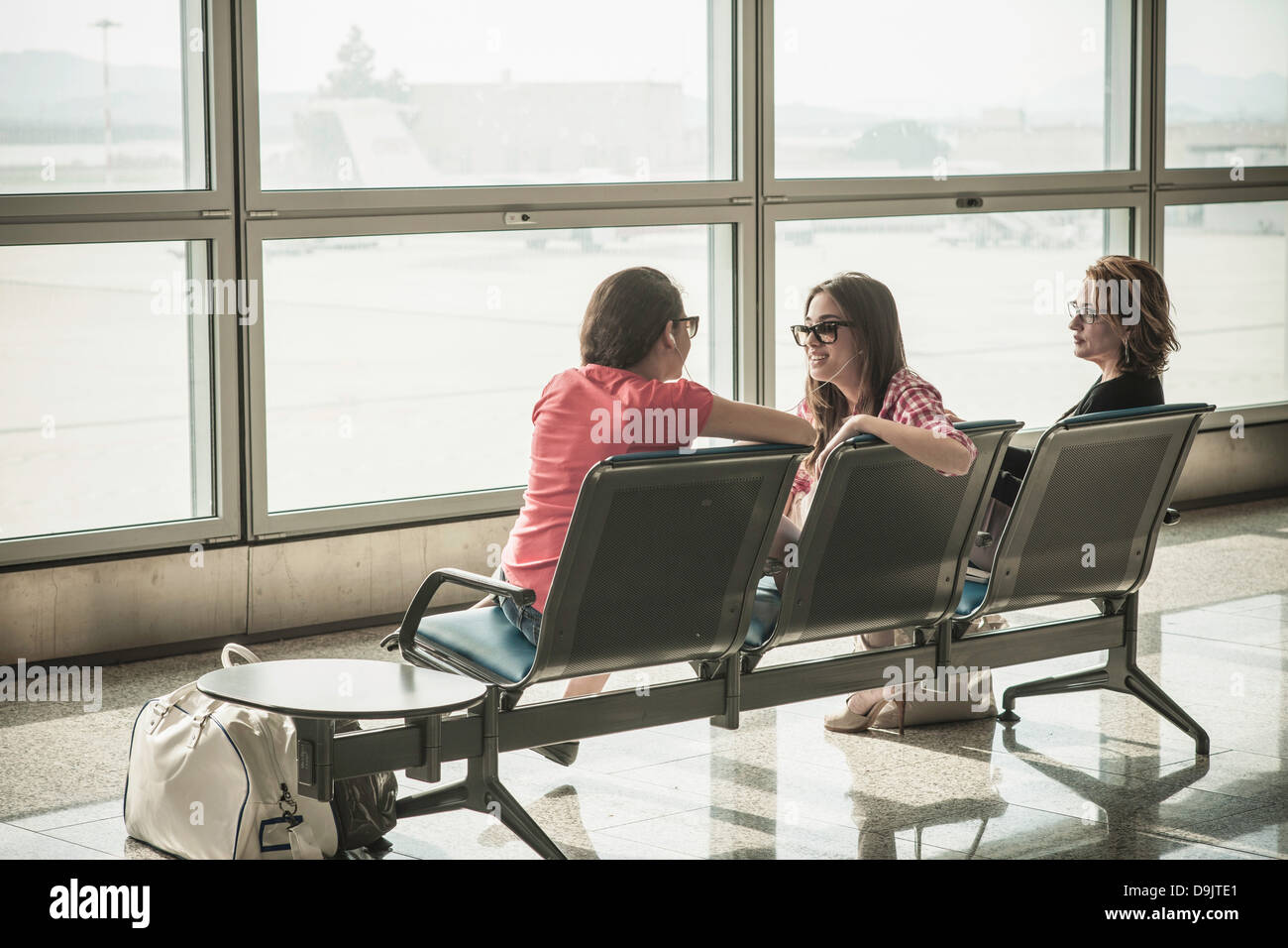 Two teenage girls and woman sitting in airport departure lounge Stock ...