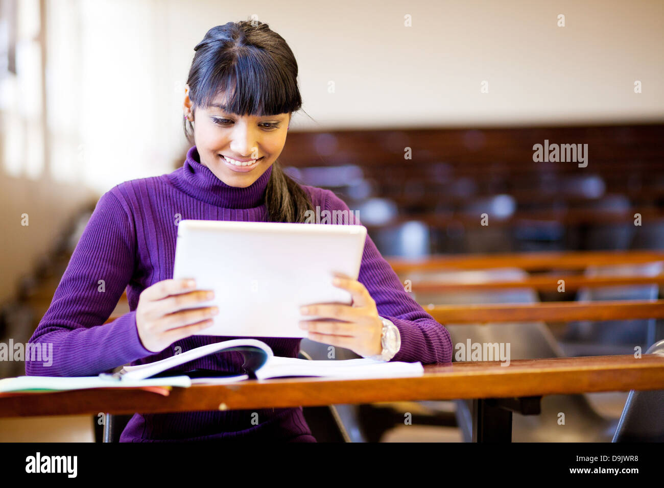 happy female Indian college student using tablet computer in classroom ...