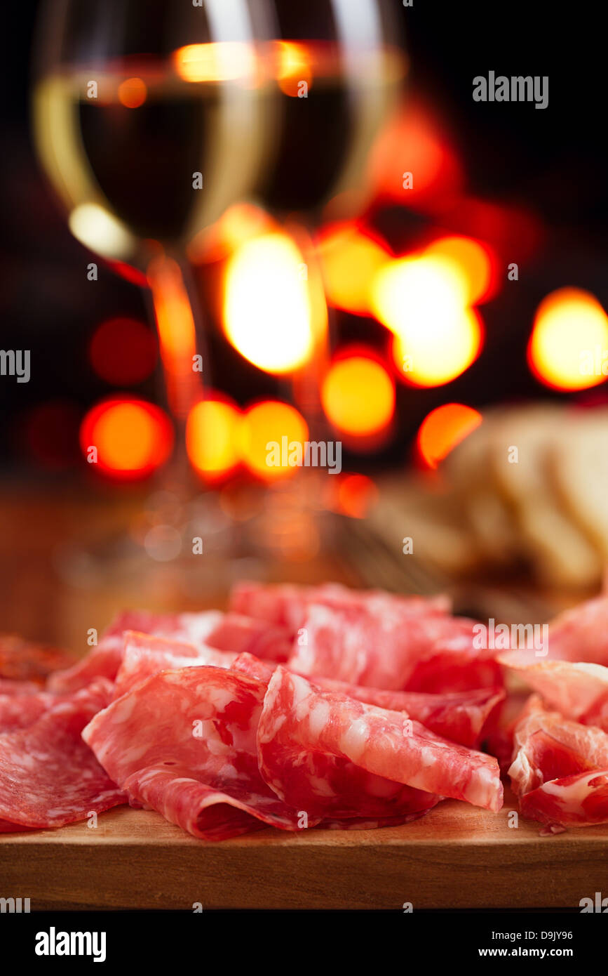 Platter of serrano jamon Cured Meat with cozy fireplace and wine ...