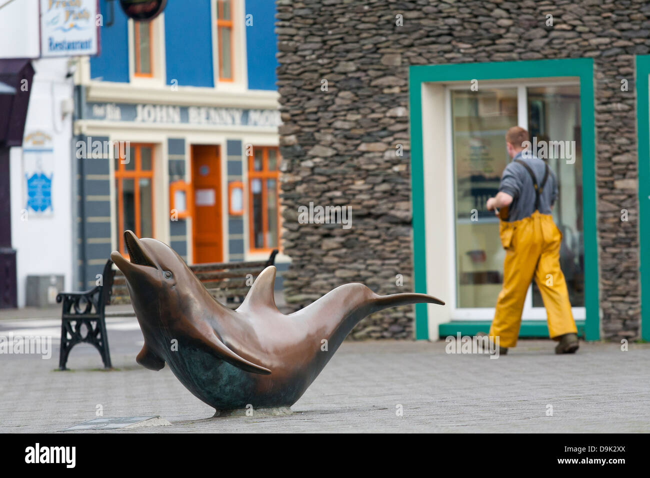 A fisherman walks past the bronze statue of Fungie the Dolphin on the ...