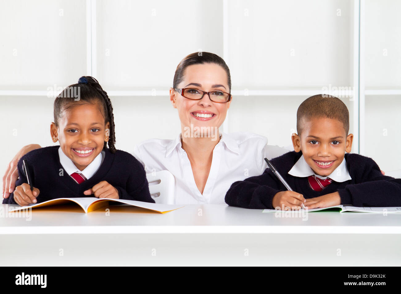 caring primary teacher and students in classroom Stock Photo - Alamy