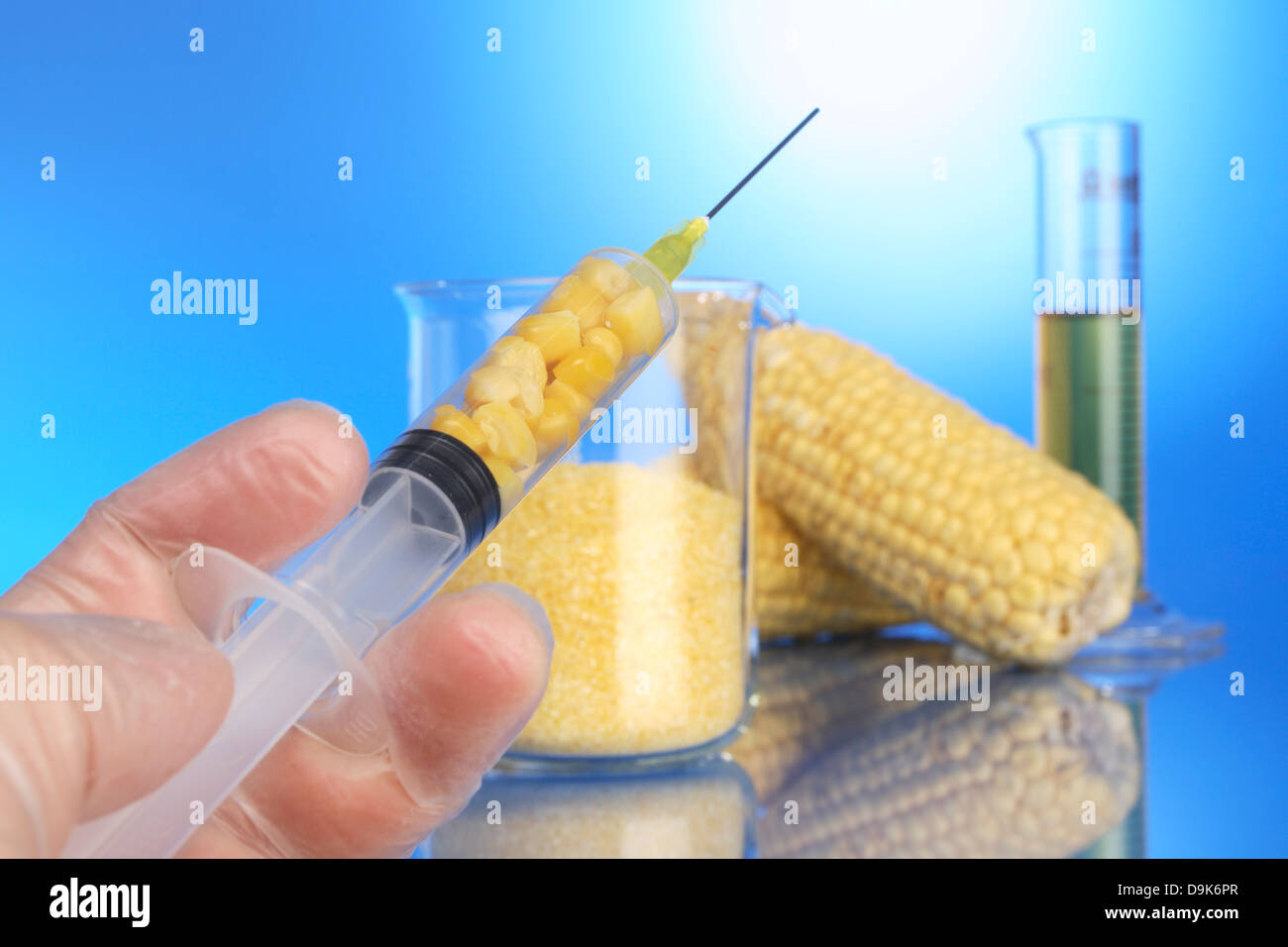 Hand with syringe, measuring mug and maize Stock Photo - Alamy