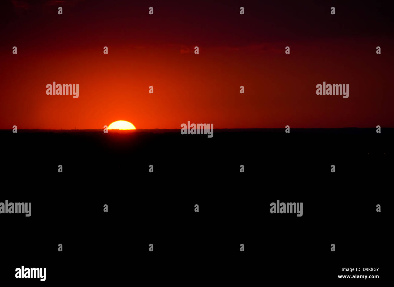 Intense red dark sky illuminated by the setting sun on the horizon ...