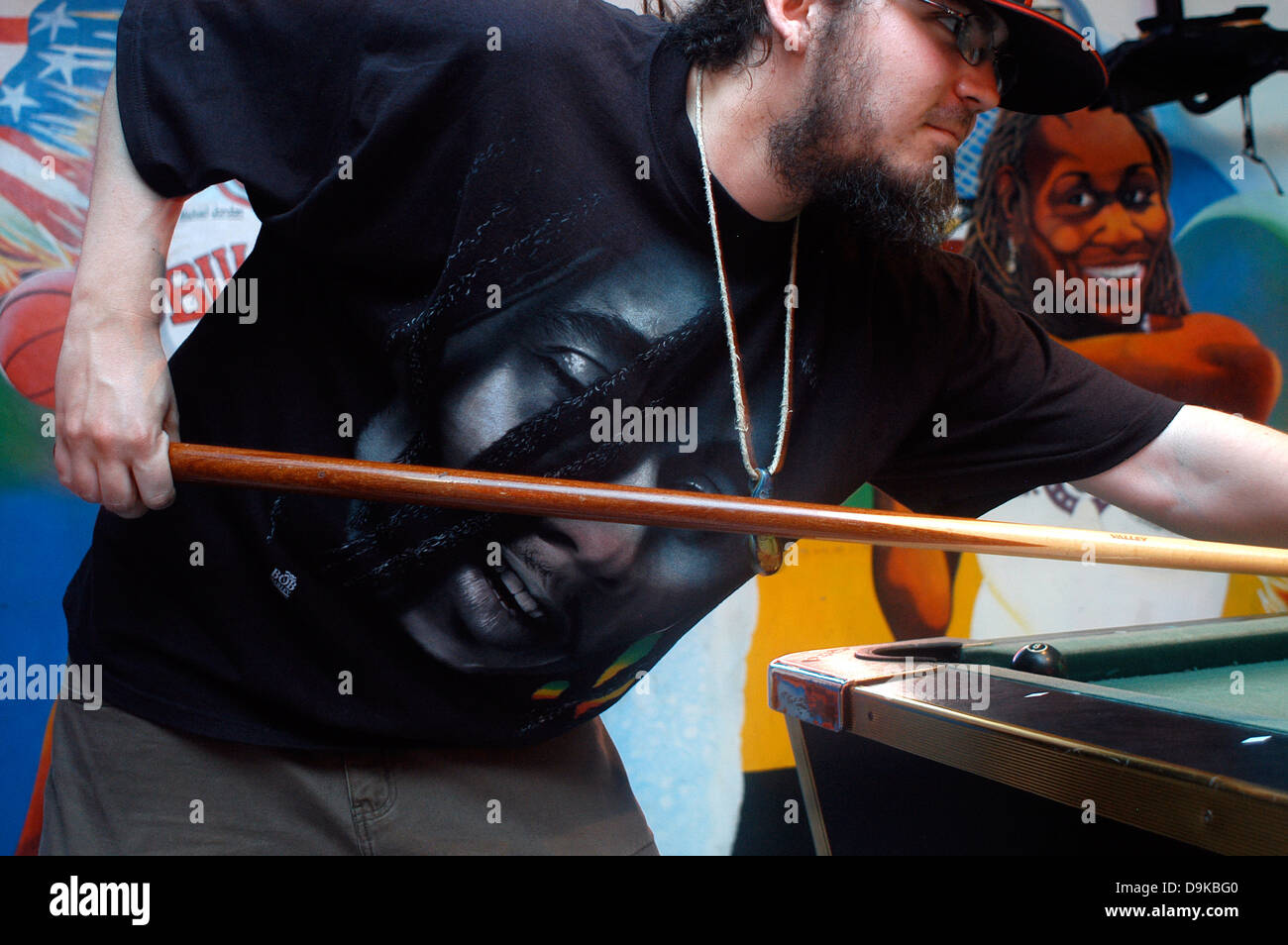 Young man playing pool at the Bar The Love Boat, Bob Marley T-shirt ...