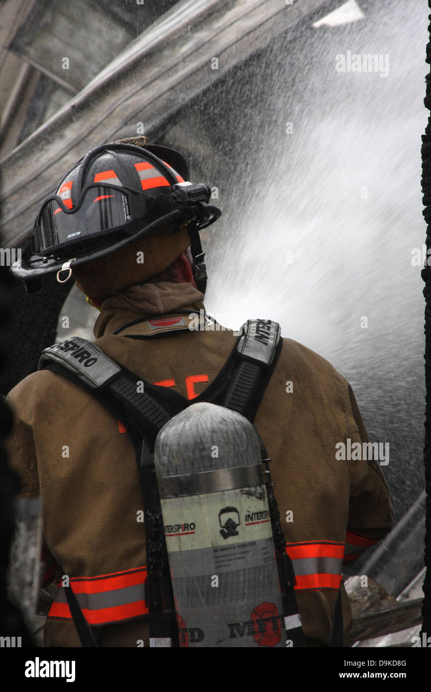 A firefighter spraying water on a fire in a collapsed building Stock ...