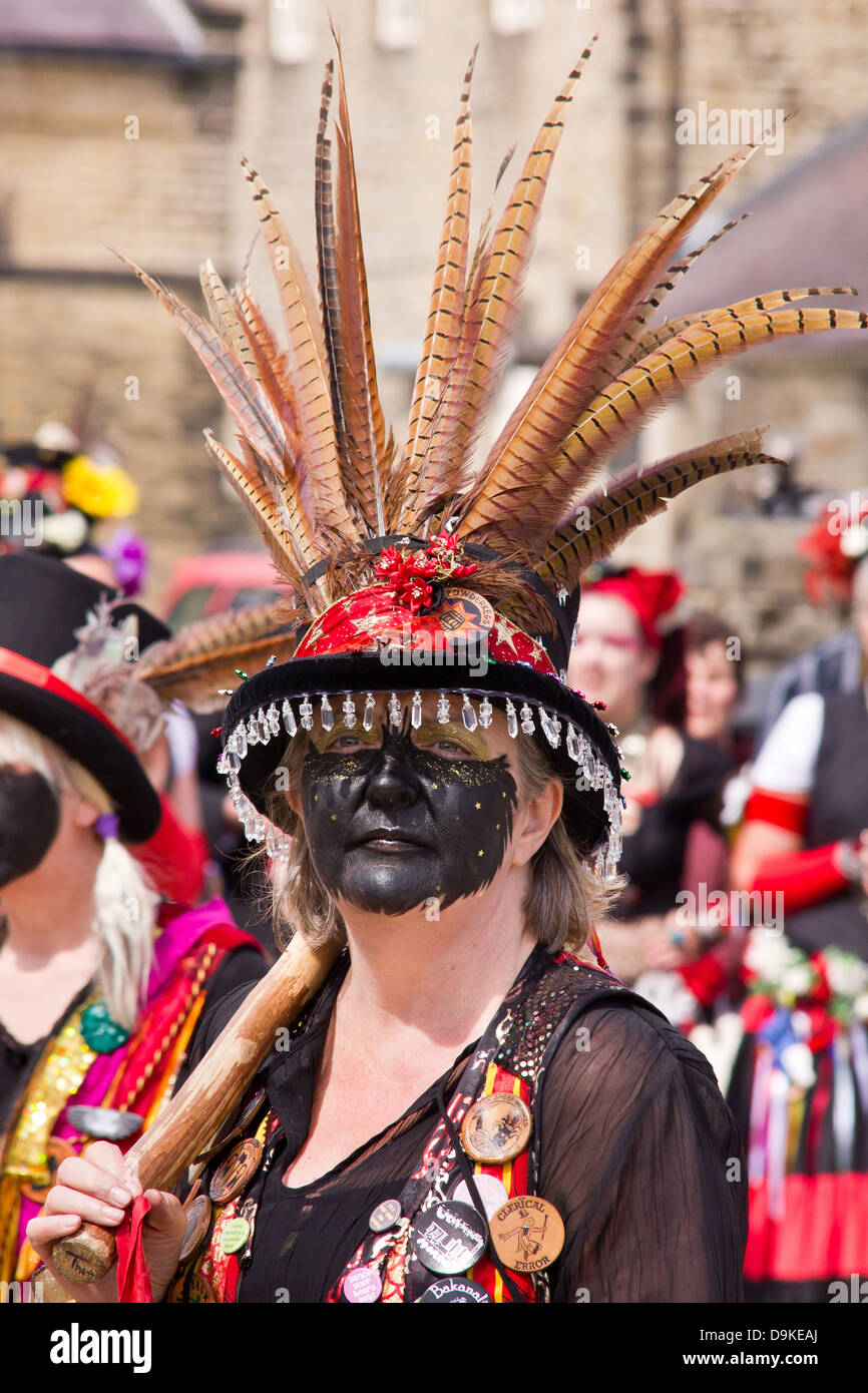 female Morris dancer with black face and feathers in her hat at Skipton ...