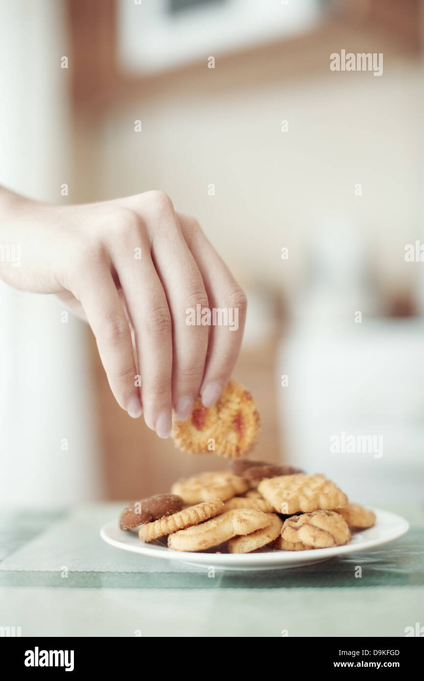 Human hand taking cookie in plate on a table Stock Photo - Alamy