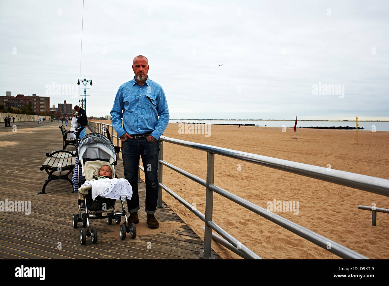Man with baby boy in push chair at seaside Stock Photo - Alamy