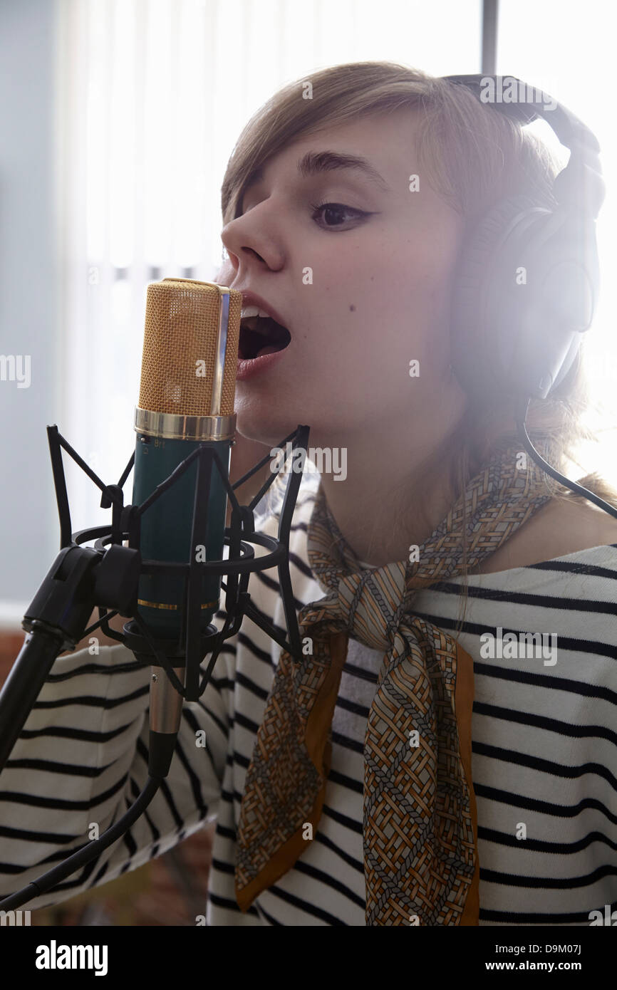 Young woman singing into microphone Stock Photo - Alamy