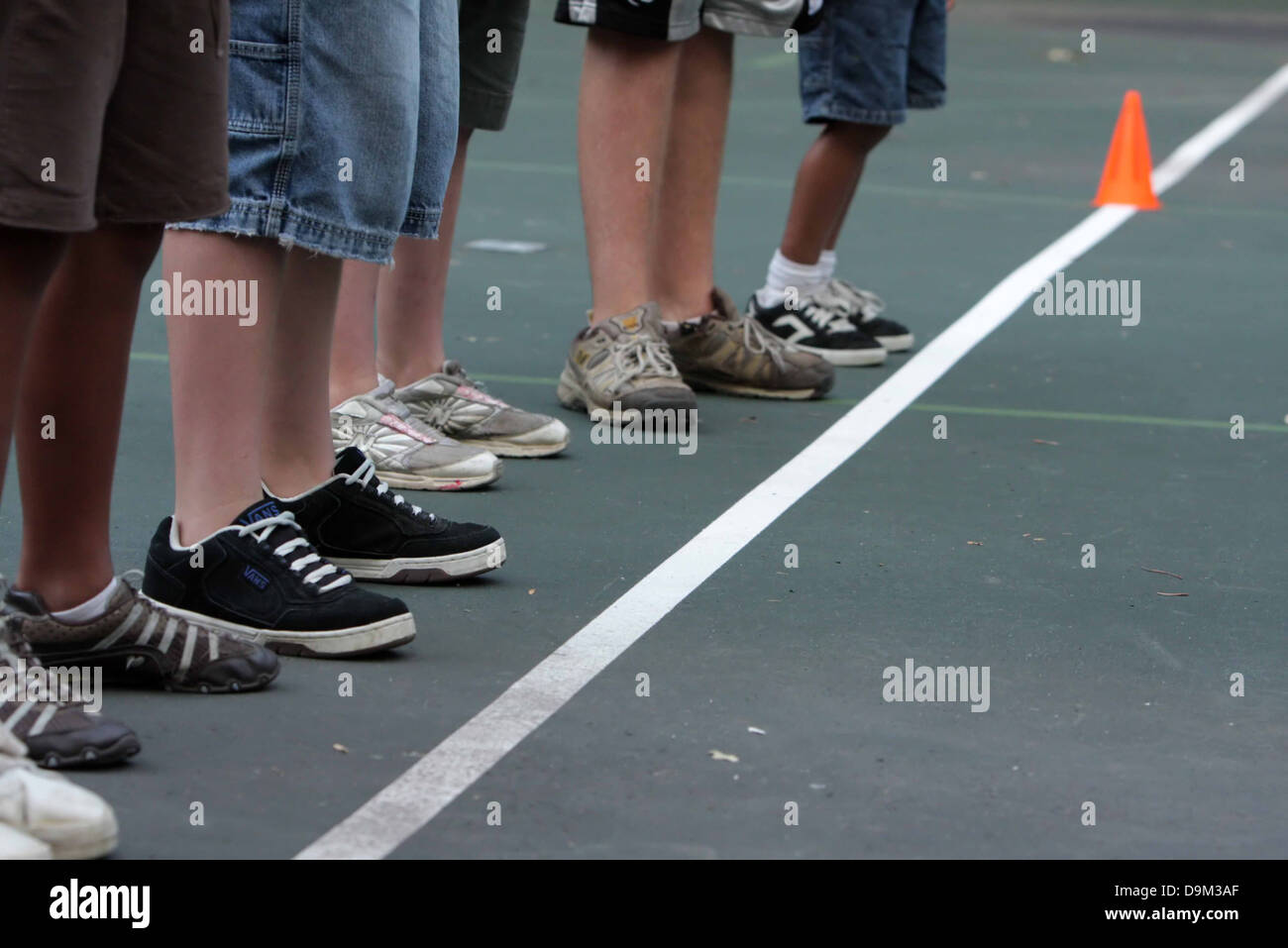 children, kids, feet and shoes, standing in line on white painted line ...