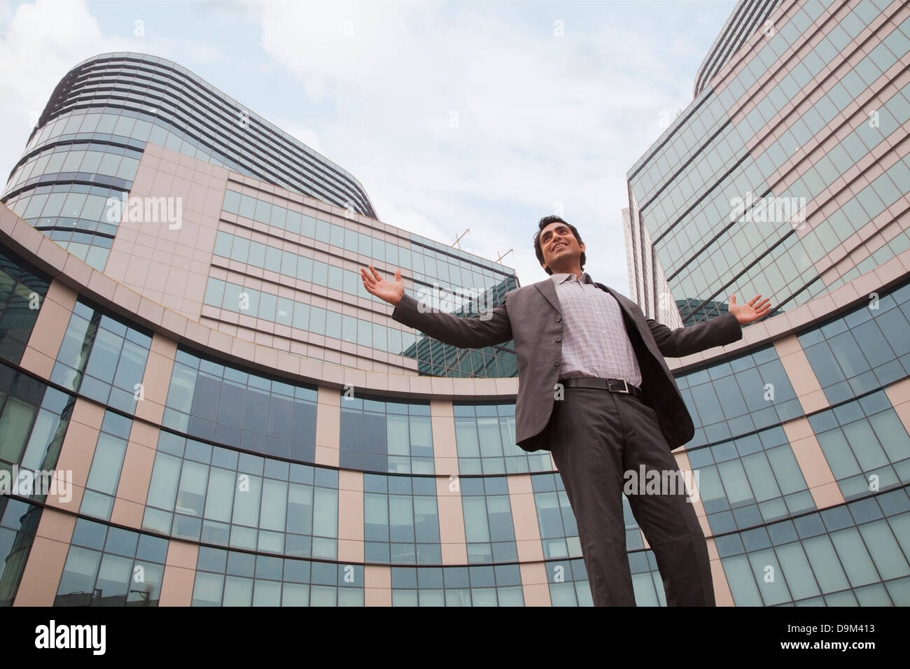 Businessman standing outside an office building with his arms ...