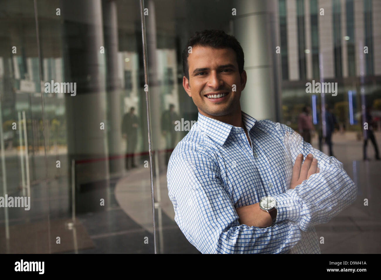 Businessman leaning against a glass wall in office Stock Photo - Alamy